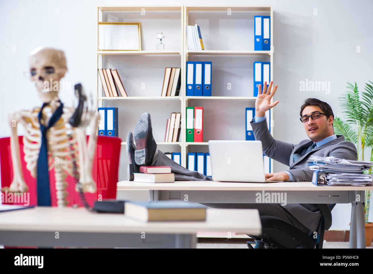 Businessman working with skeleton in office Stock Photo - Alamy