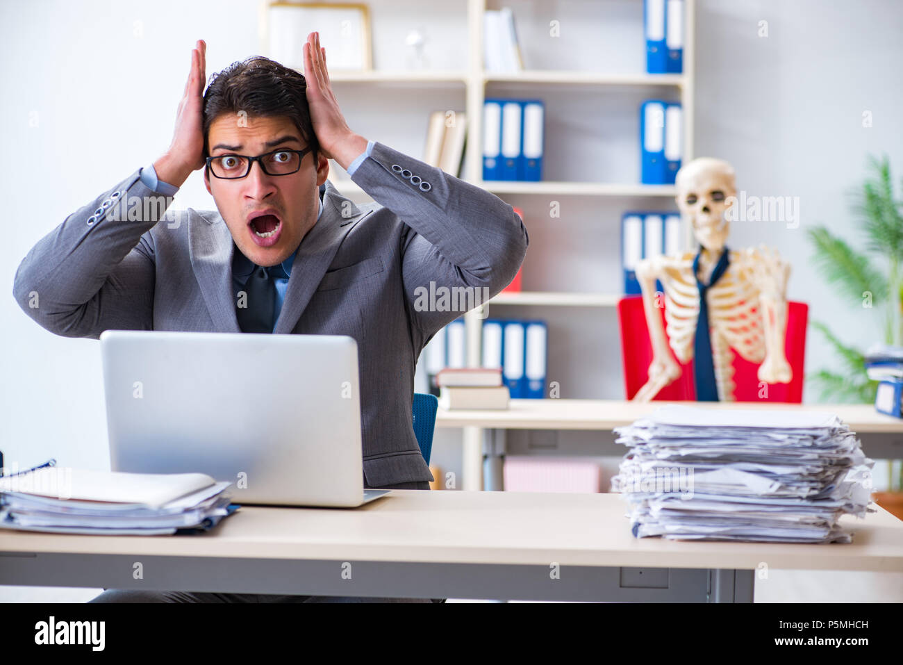 Businessman working with skeleton in office Stock Photo - Alamy