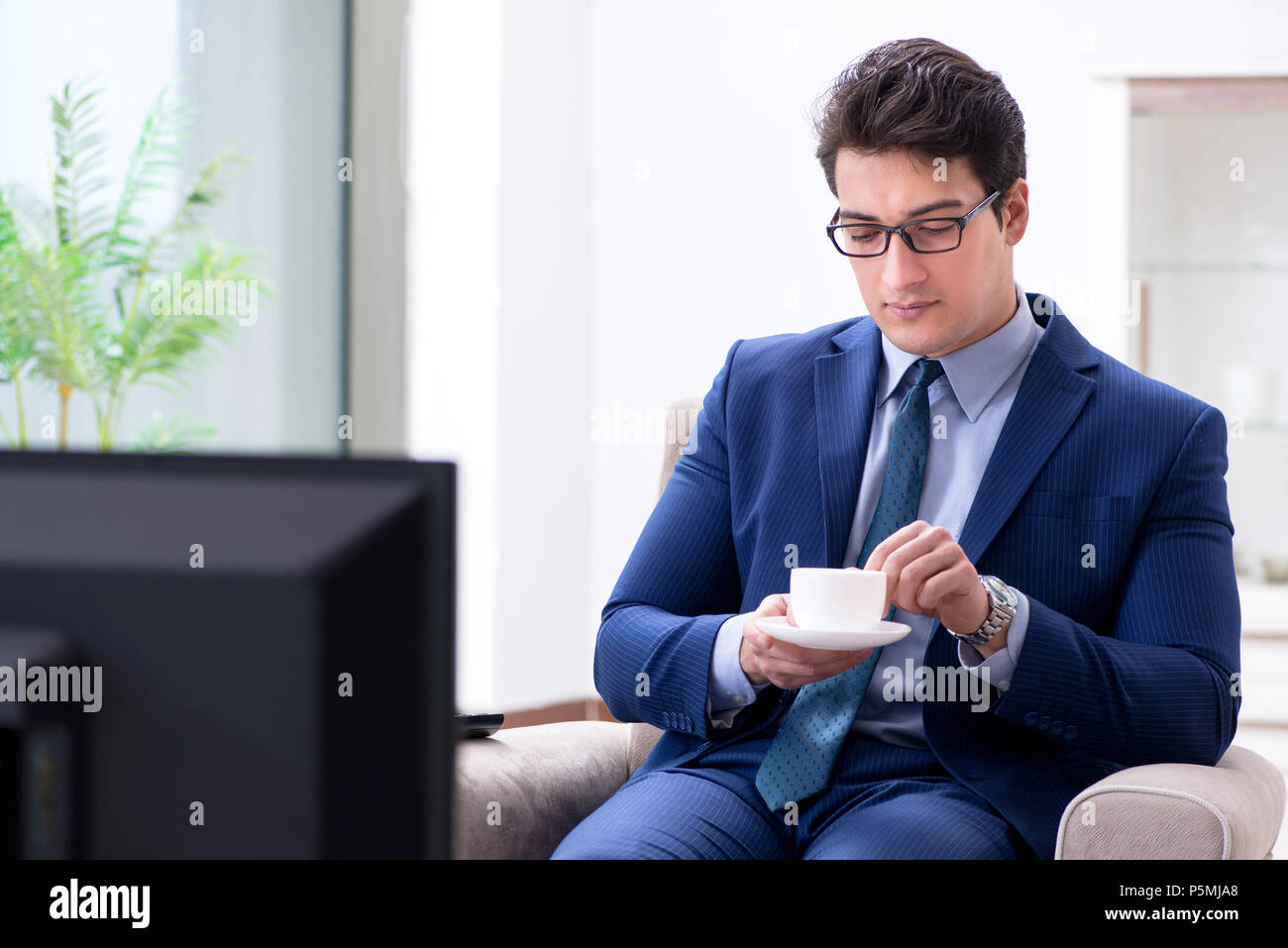 Businessman watching tv in the office Stock Photo - Alamy