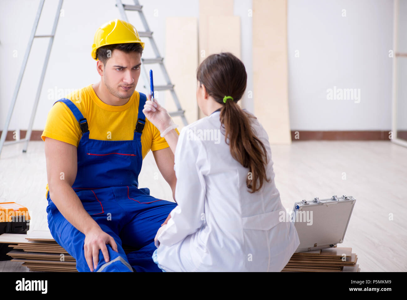 Doctor helping injured worker at construction site Stock Photo - Alamy