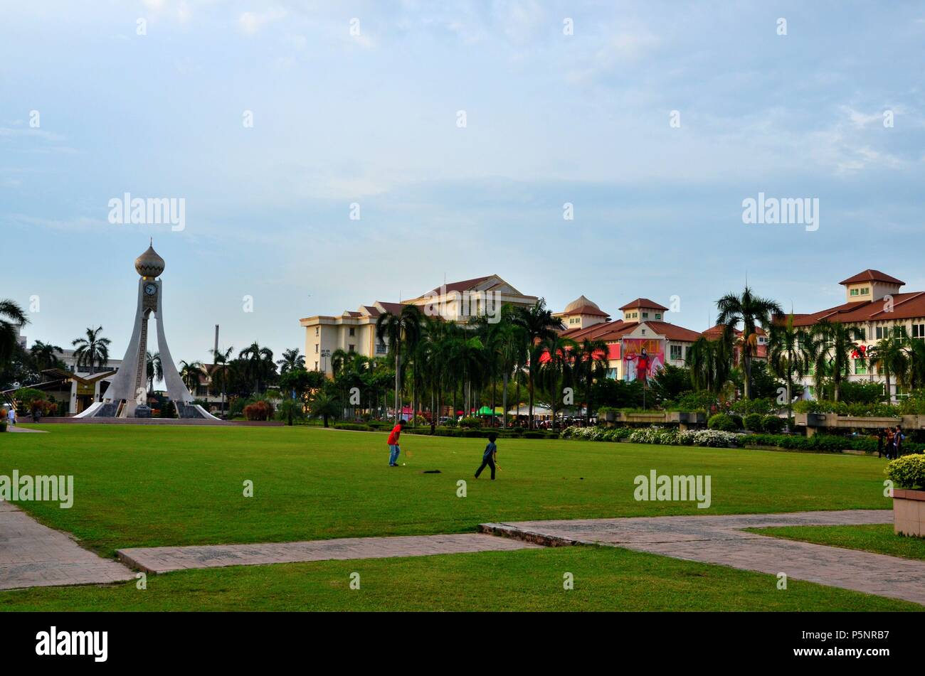 Malay kids play badminton in grass field at Dataran gardens with clock ...