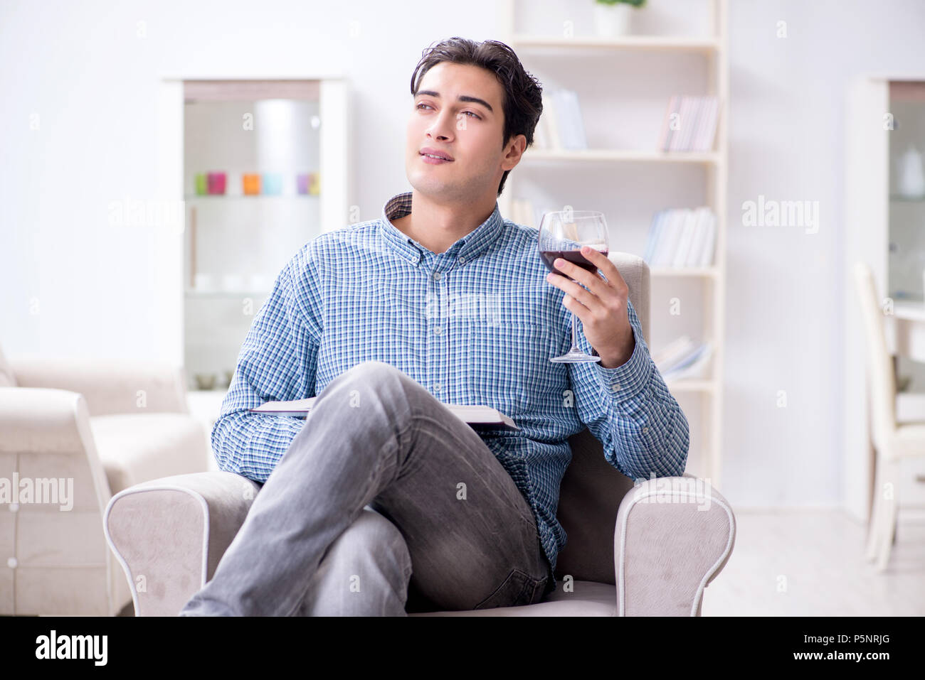 Young man drinking wine at home Stock Photo - Alamy