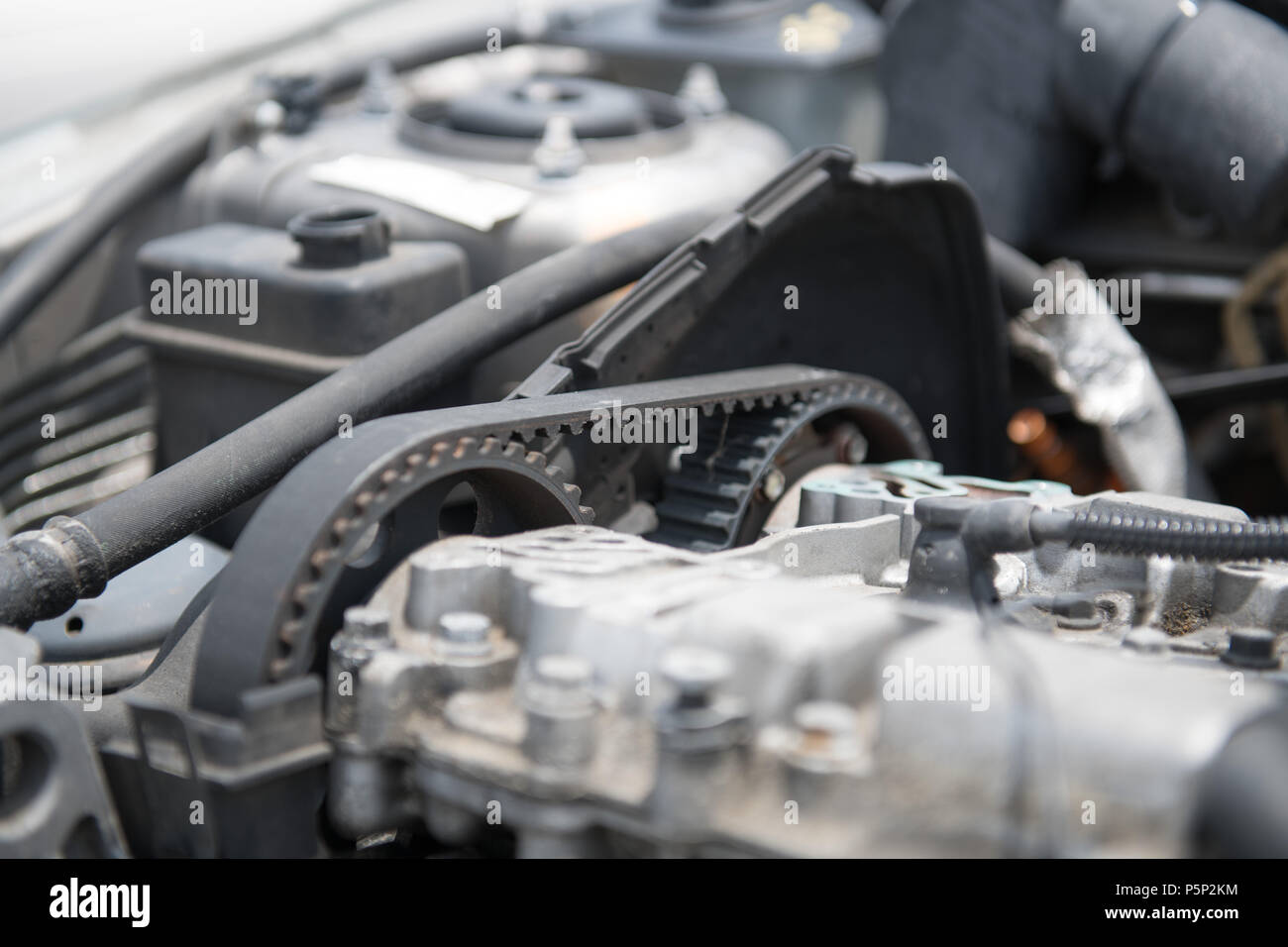 The timing belt of an automobile engine is visible on the side of the ...