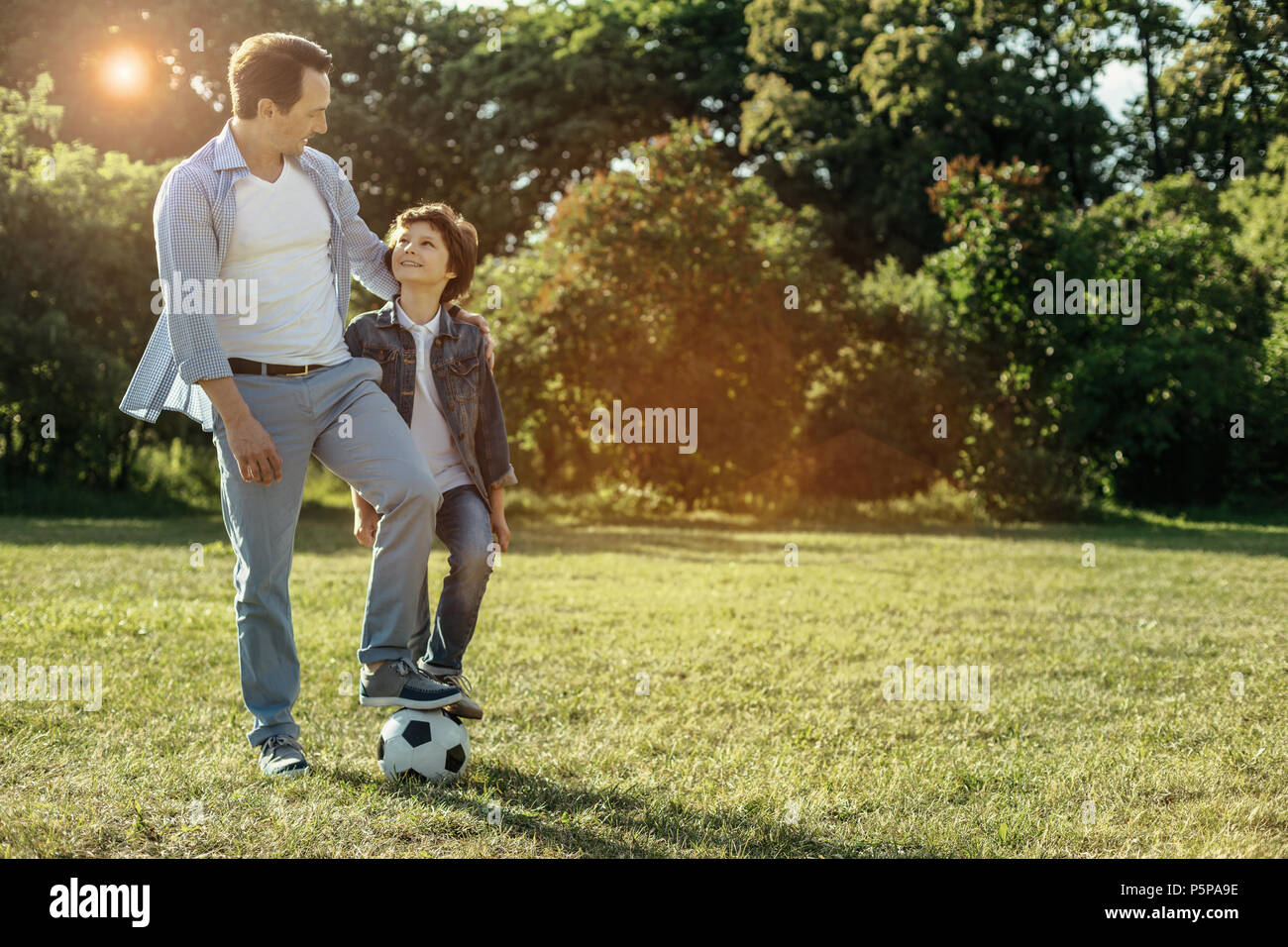 Dad and boy having a rest while playing football Stock Photo - Alamy