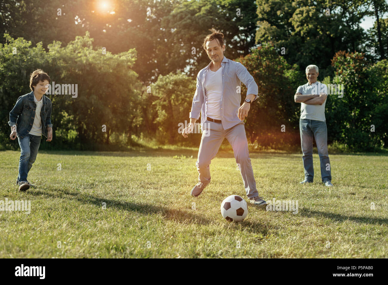 Happy family playing football outdoors Stock Photo - Alamy