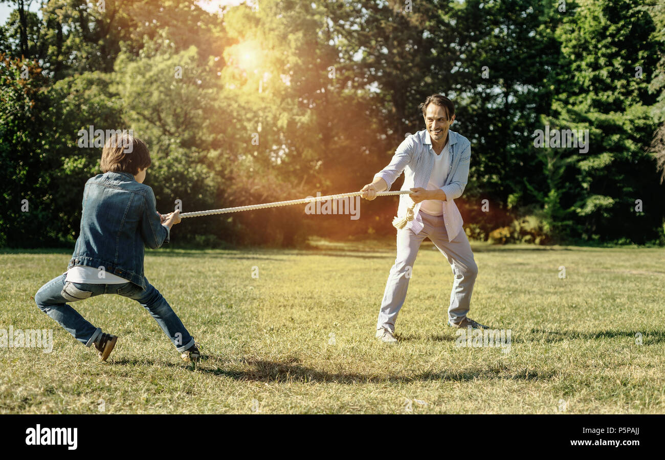Dad and son playing rope-pulling in nature Stock Photo - Alamy