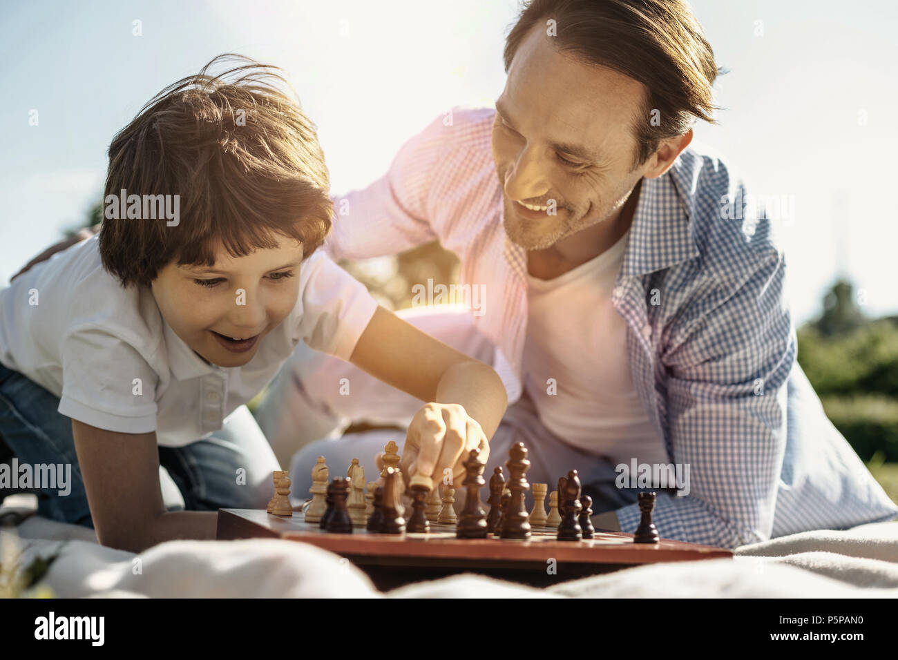 Smiling son and dad playing chess Stock Photo - Alamy