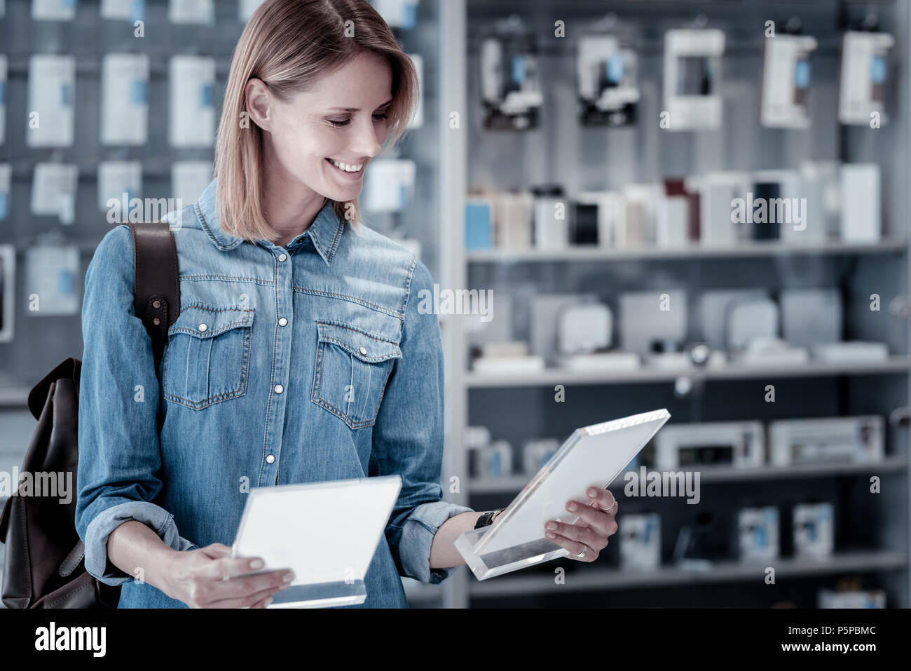 Happy young woman reading two different descriptions Stock Photo - Alamy