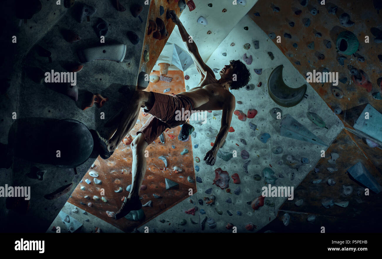 Free climber young man climbing artificial boulder indoors Stock Photo ...
