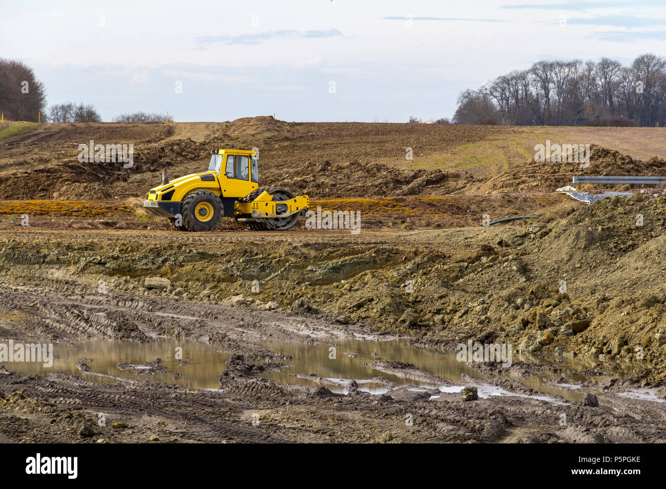 yellow roller compactor at a loamy construction site Stock Photo - Alamy