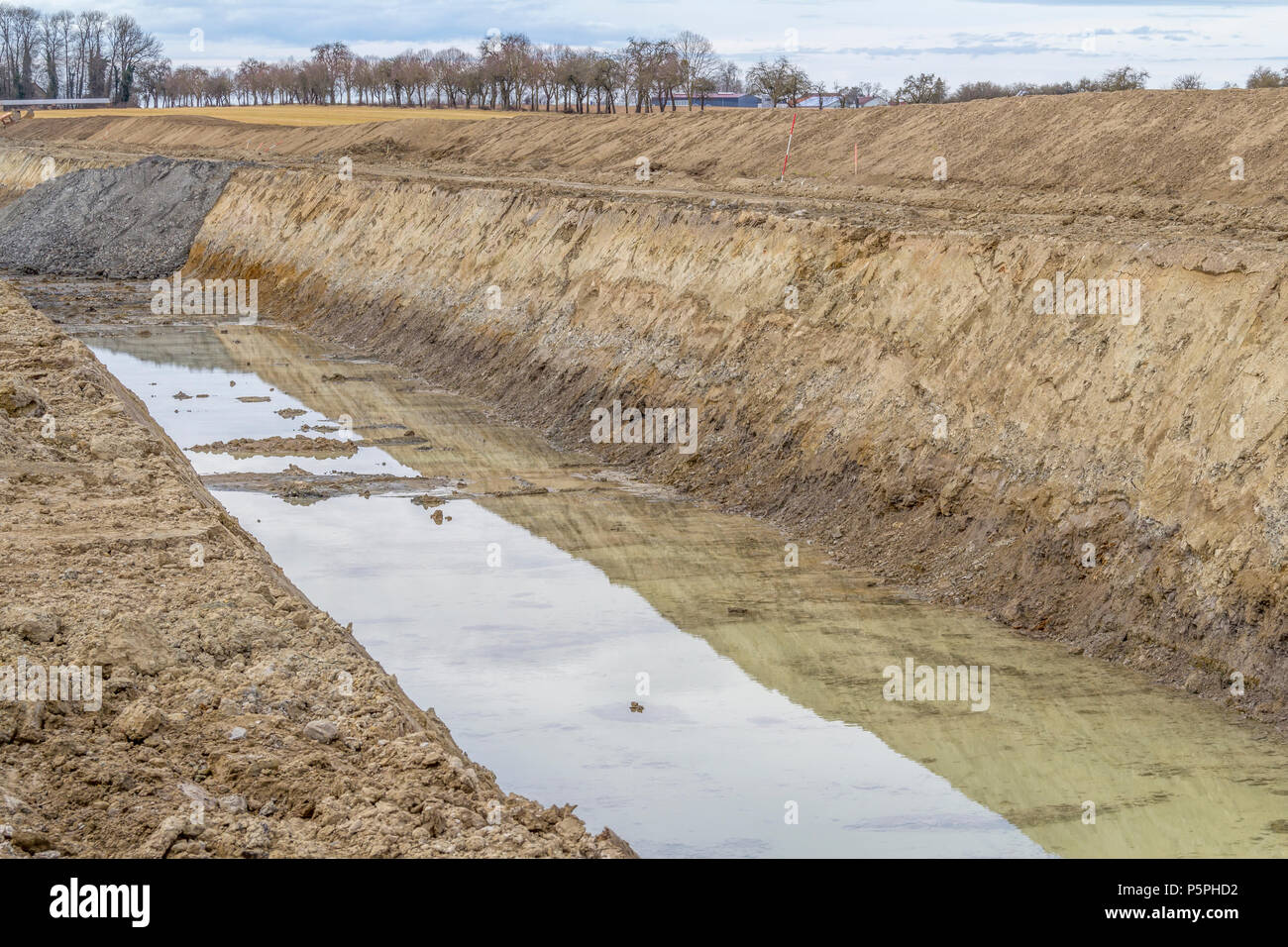 construction site including a big trench with lots of earth and loam ...