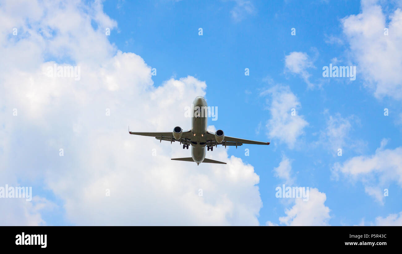 Jet passenger airplane shot from below against a blue sky with clouds ...
