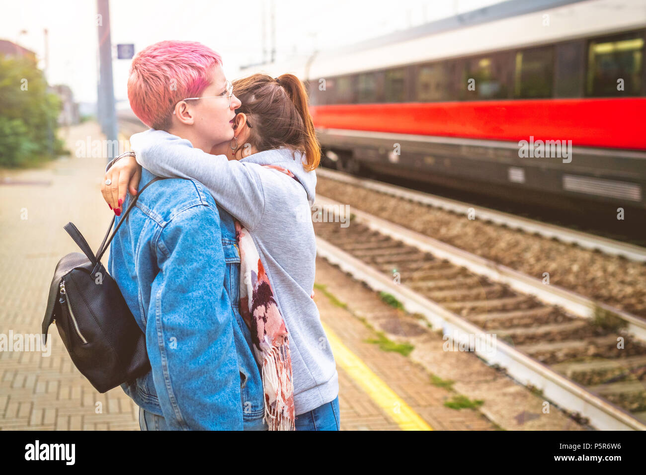 two young women outdoors hugging train station - farewell, leaving ...