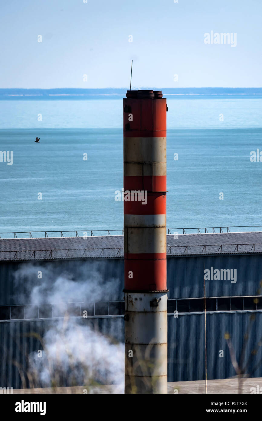 Industrial sea port with tall pipe Stock Photo - Alamy