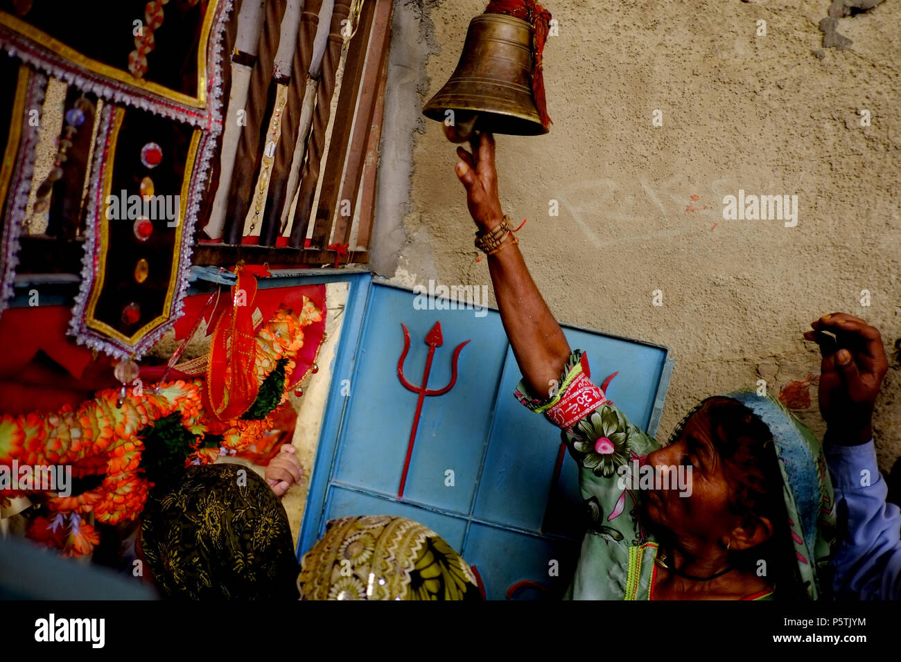 A woman rings a bell at the Hindu temple of the Red Goddess know as the ...