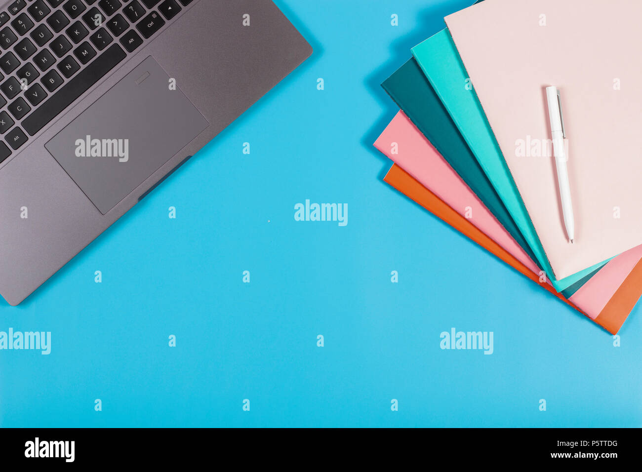 Workspace with laptop keyboard and colorful notebooks on blue ...