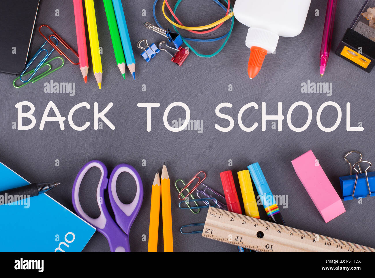 Overhead view of a border of school supplies on a blackboard with BACK ...
