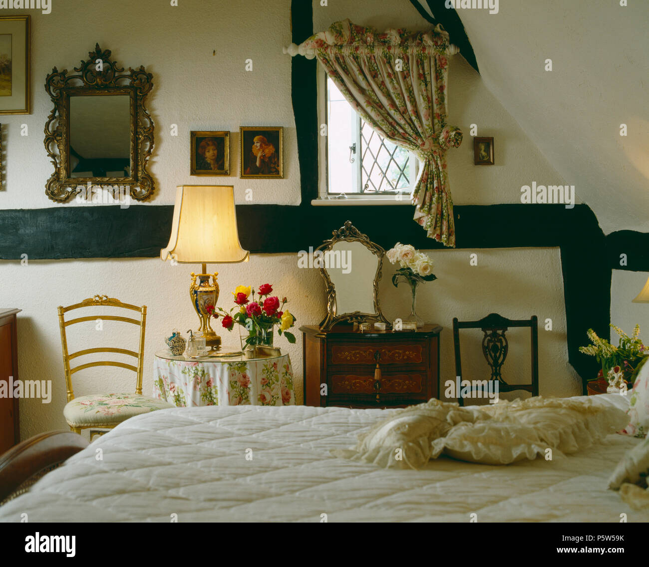 Attic cottage bedroom with floral curtain at small window and lighted ...