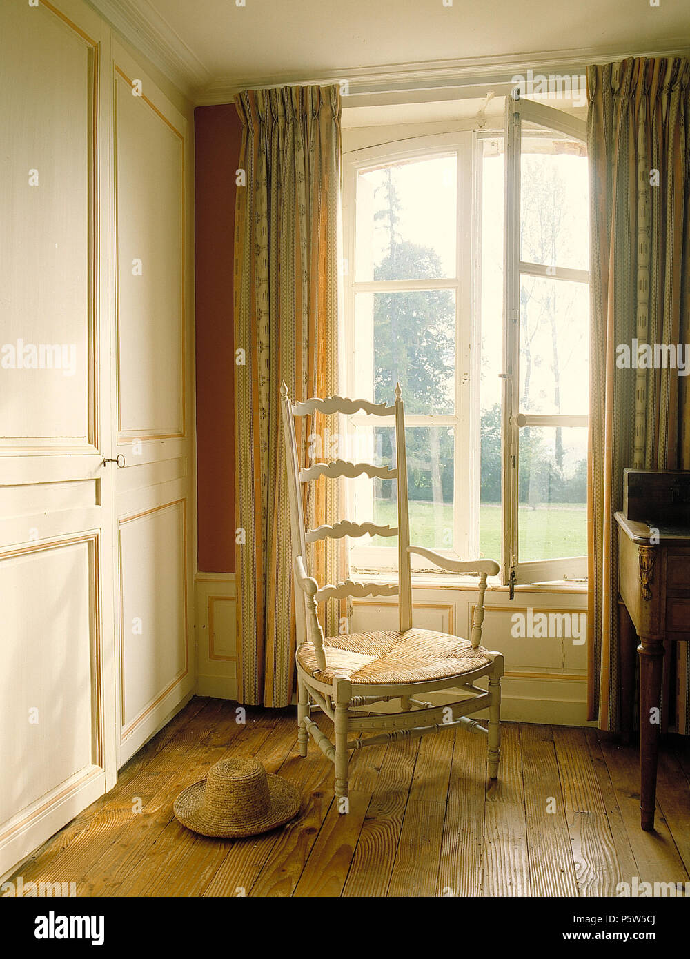 Rush seated ladderback chair in front of open windows in French country ...