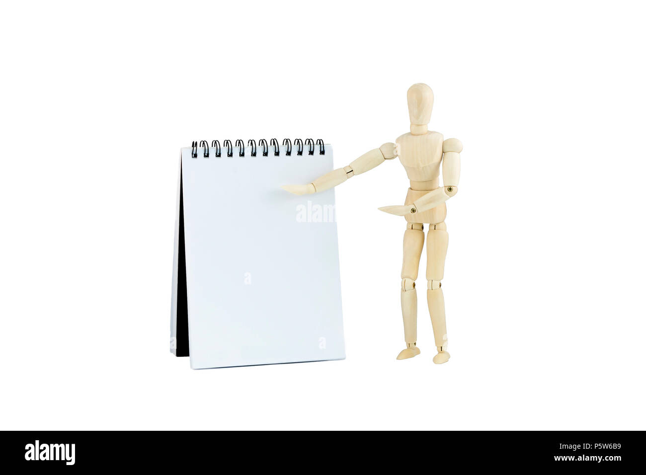 articulated wooden dummy indicating something in a notebook on white ...