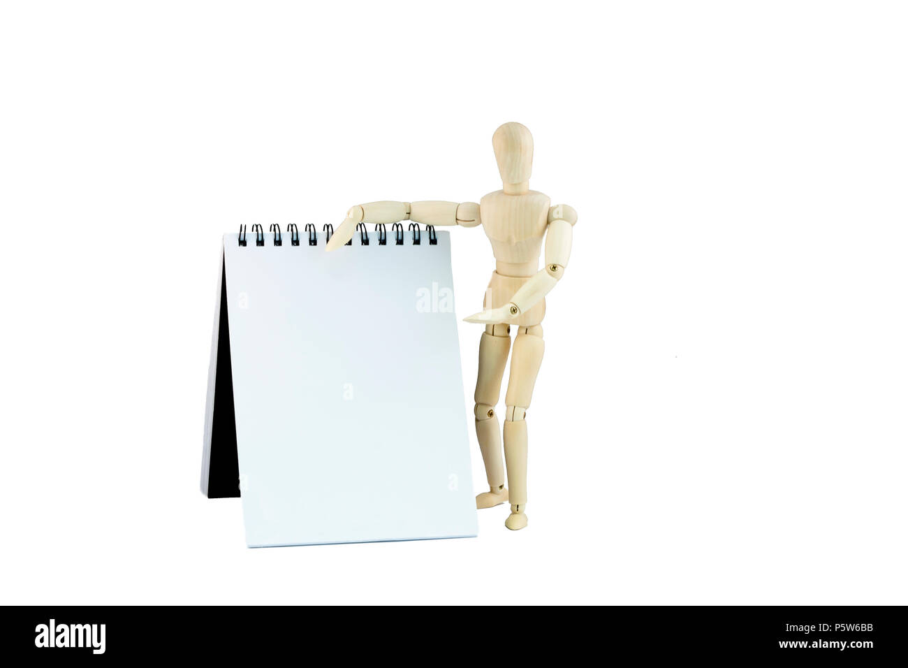 articulated wooden dummy indicating something in a notebook on white ...