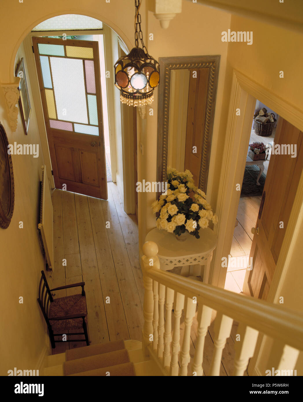 Looking down staircase at hall with wooden flooring and stained-glass ...
