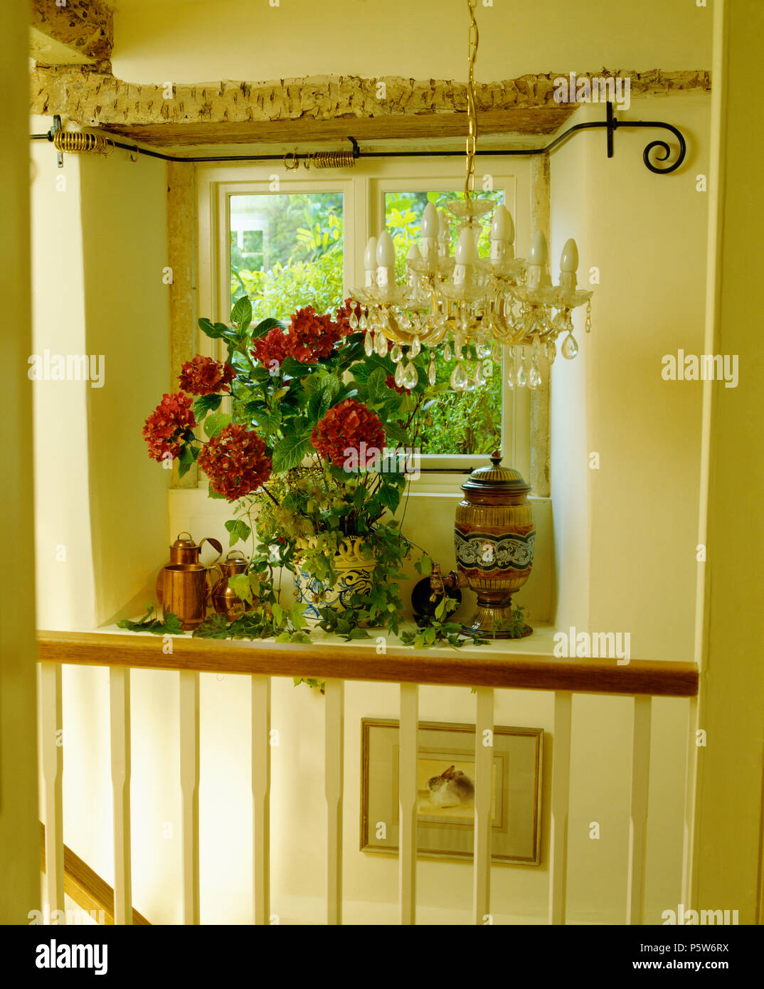 Summer flowers in jug on windowsill of small recessed window above ...