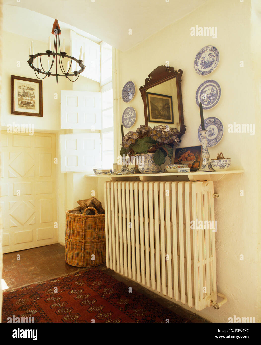Blue+white plates on either side of vintage mirrorabove cream radiator ...