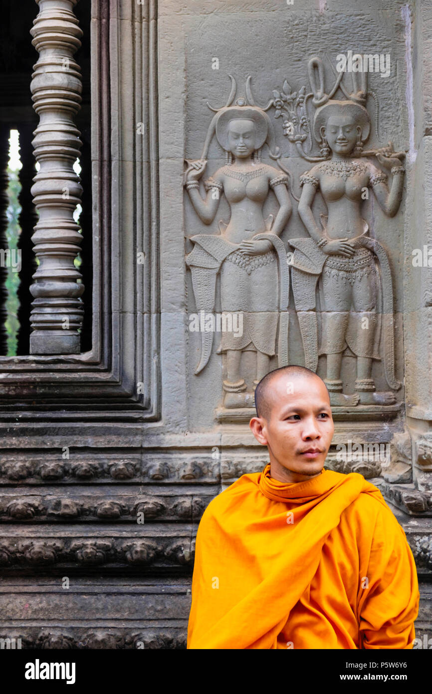 Buddhist monk in front of carvings of dancing apsara nymphs at Angkor ...