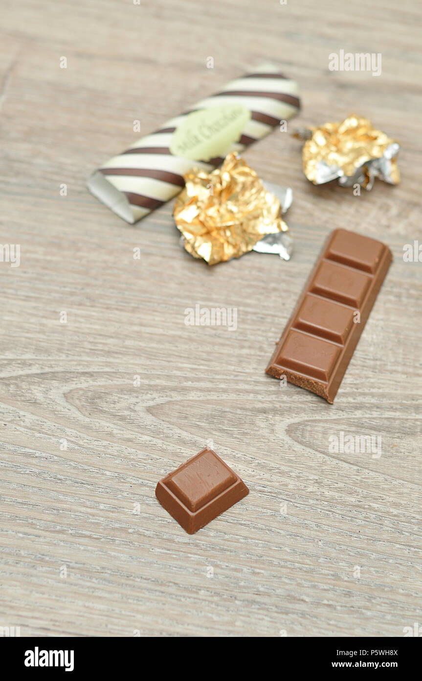 A chocolate candy bar with a piece broken off with the wrappers out of ...
