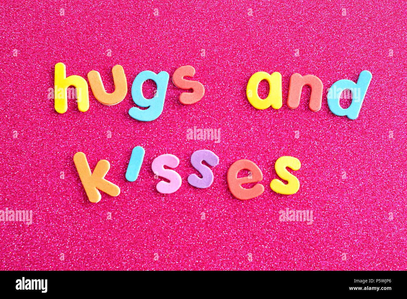 The words hugs and kisses on colorful letters on a pink background ...