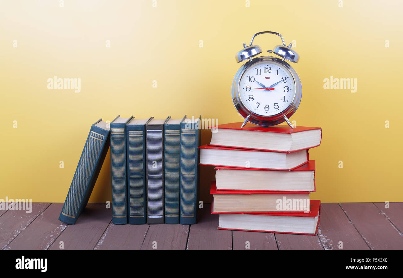 Science and education - alarm clock and pile group of colorfull books ...