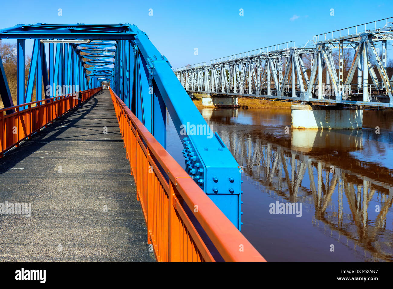 Iron structures of a pedestrian bridge with rails and arches on a sunny ...