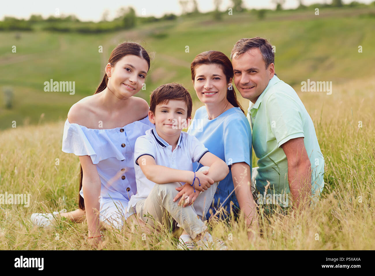Portrait of a happy family sitting on nature in the grass Stock Photo ...