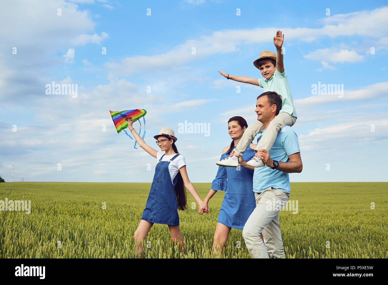 Family with a kite walking on the field in nature Stock Photo - Alamy