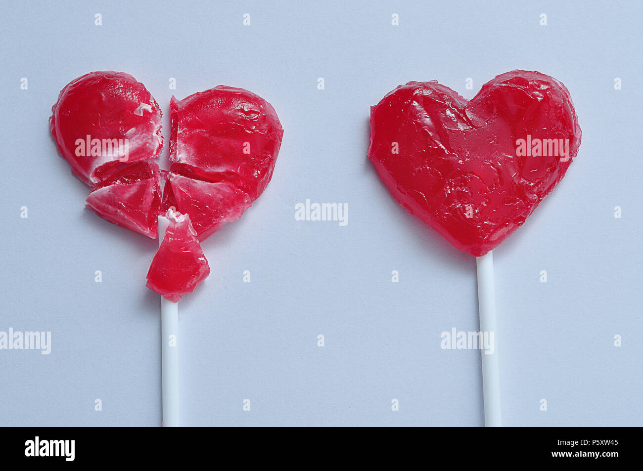 A broken red heart lollipop and a whole one symbolizing a relationship ...