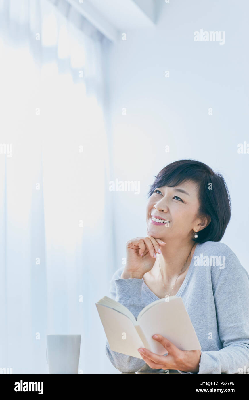 Japanese senior woman reading book at table Stock Photo - Alamy