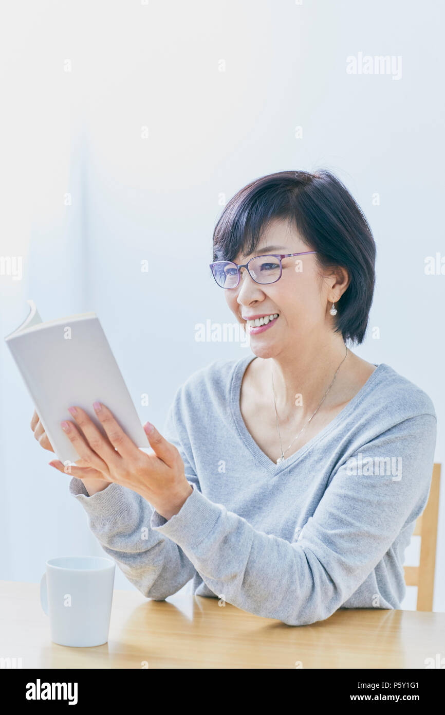 Japanese senior woman reading book at table Stock Photo - Alamy