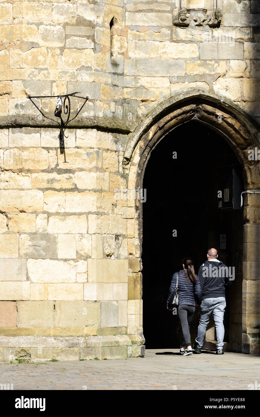 Two people walk through the Exchequer Gate arch at the precinct of the ...