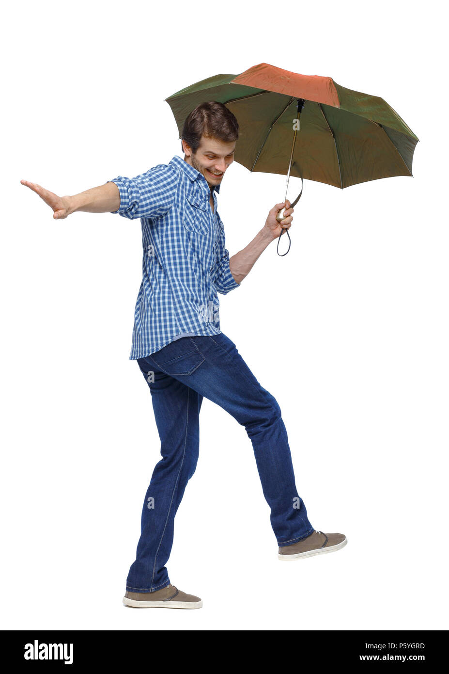 Side view of a man balancing with an umbrella. The guy jumps over a ...