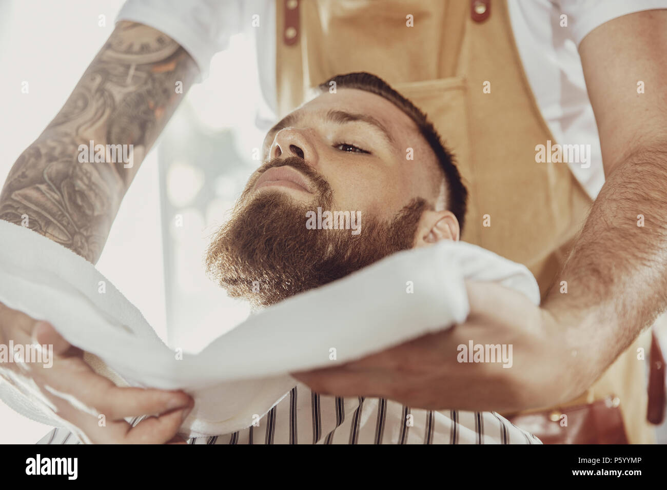 Barber covers the face of a man with a beard with a hot towel. Photo in ...