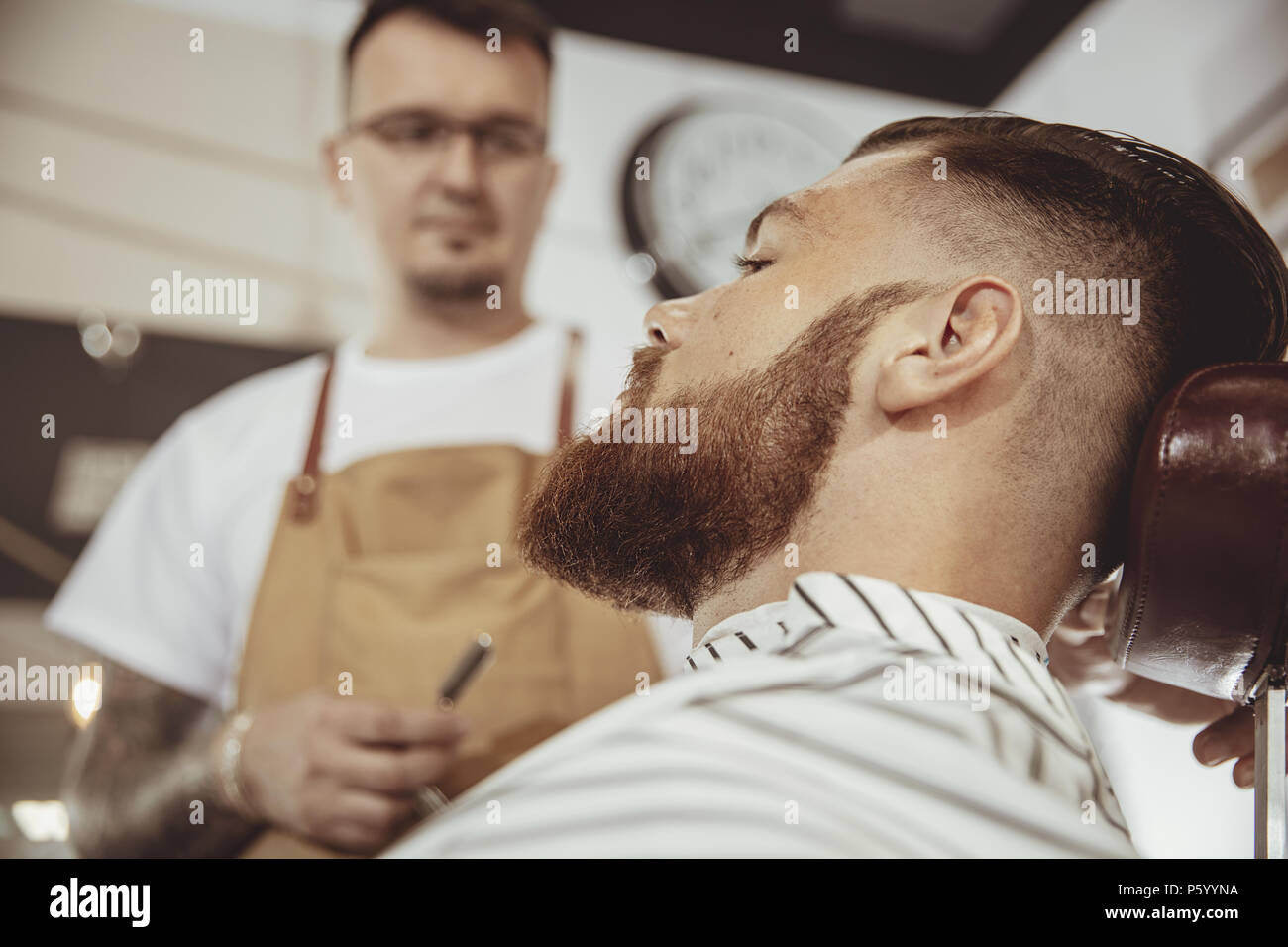 Man with beard waits for a shave with a razor in a barbershop. Photo in ...