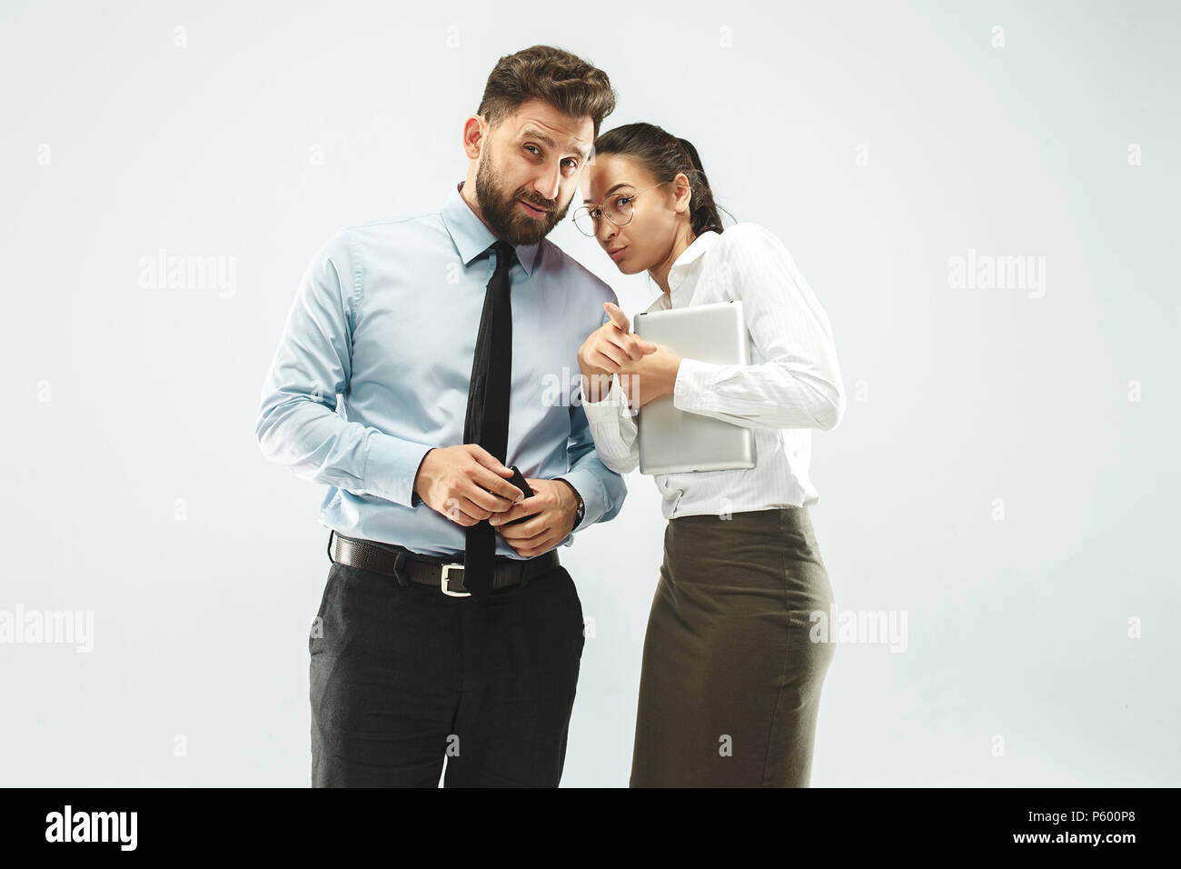 The young woman whispering a secret behind her hand over white ...