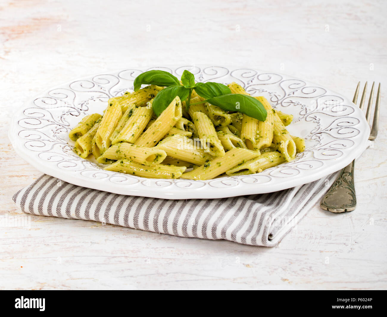 Plate of pasta type penne rigate with basil pesto, on white background ...