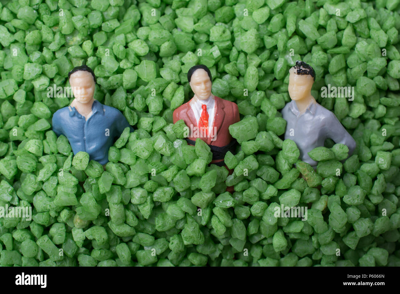 Group of tiny figurine of man in green sand Stock Photo - Alamy