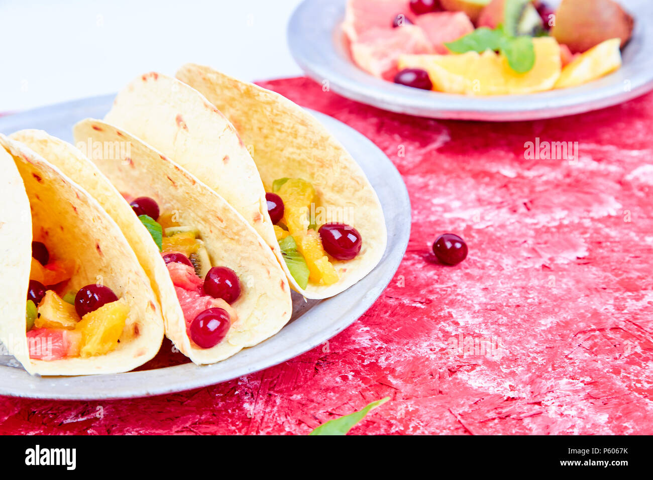 Fruit tacos with orange, kiwi, grapefruit red background and berry ...