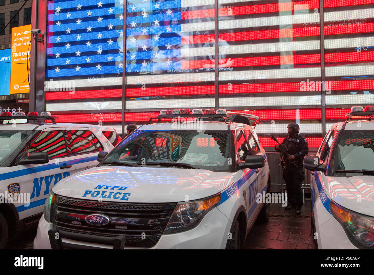 An armed NYPD cop stands in front of a neon stars and stripes in Times ...