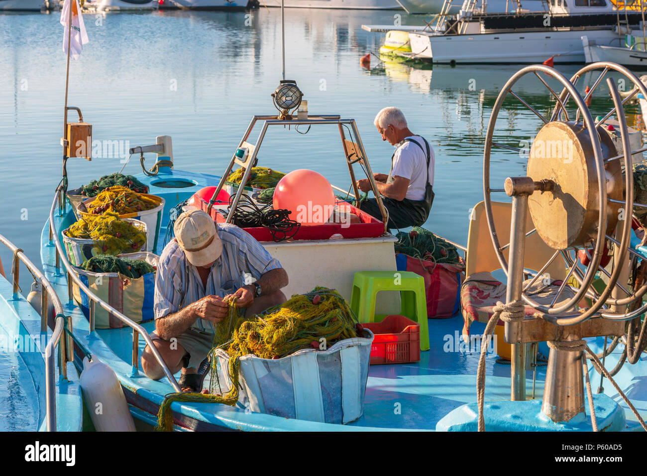 Local fishermen mending the fishing nets on a traditional styled local ...