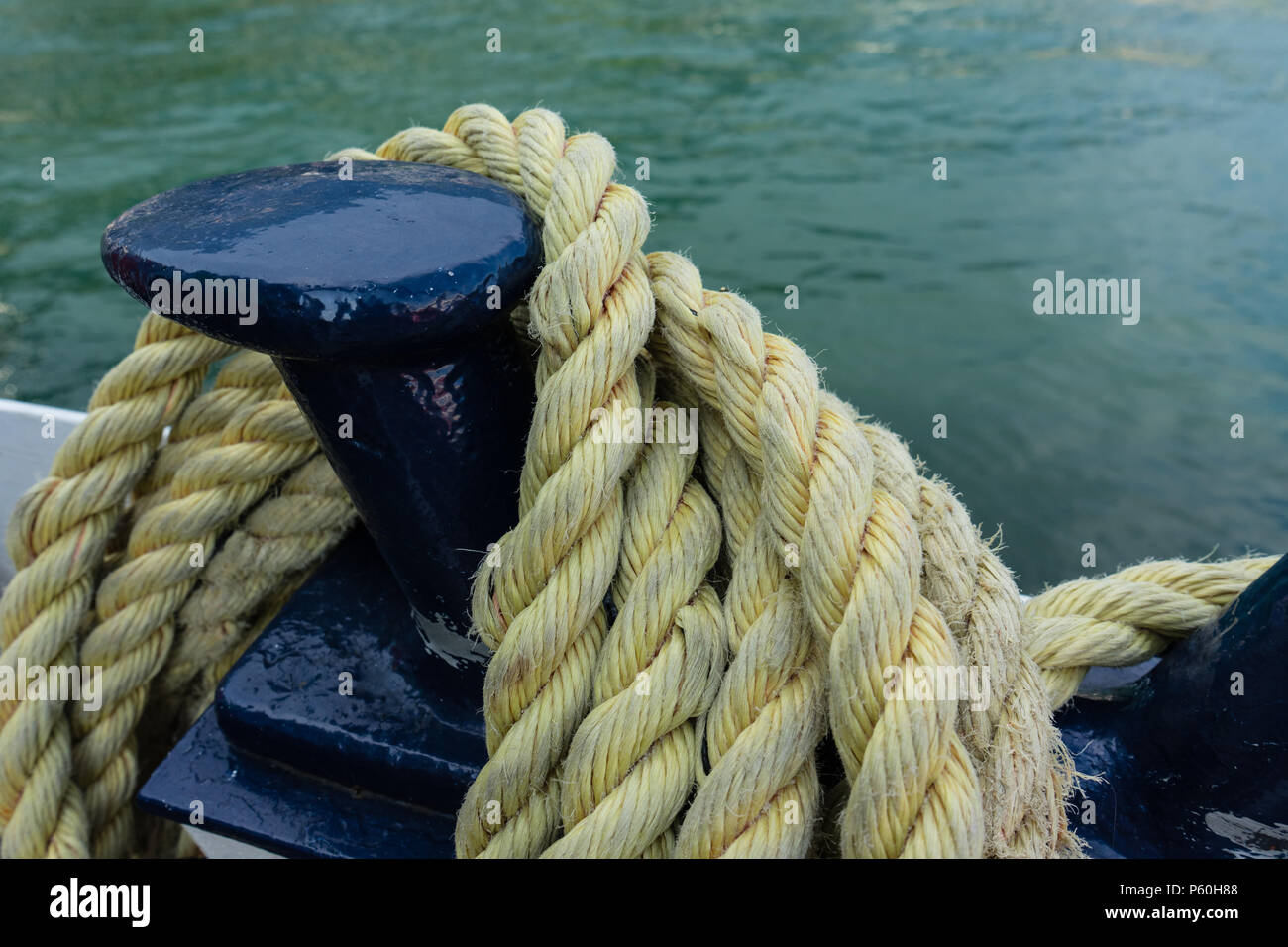 Close-up of an old yellow frayed boat rope, water background with ...