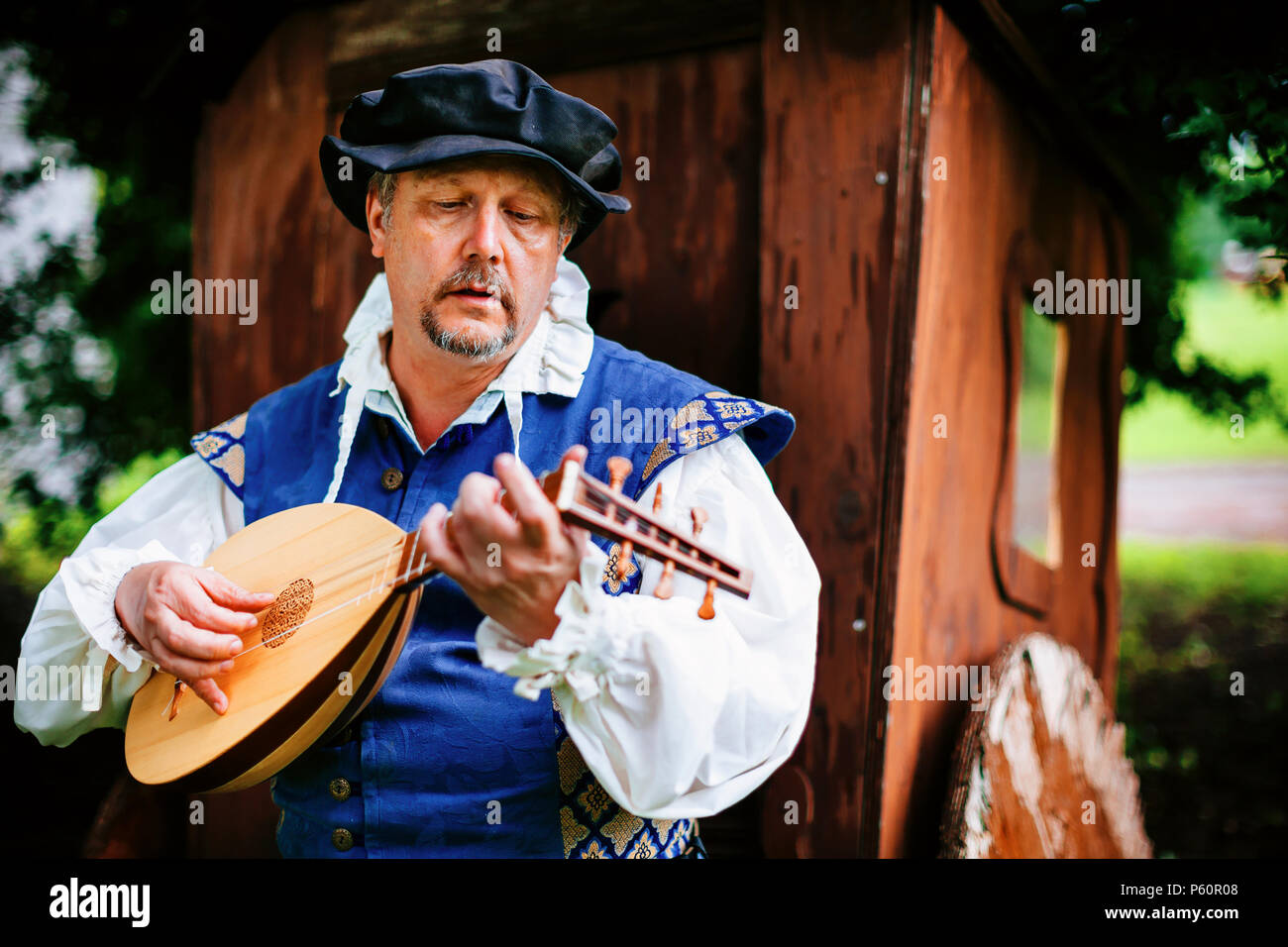A Renaissance fair actor dressed as a musician poses with his lute ...